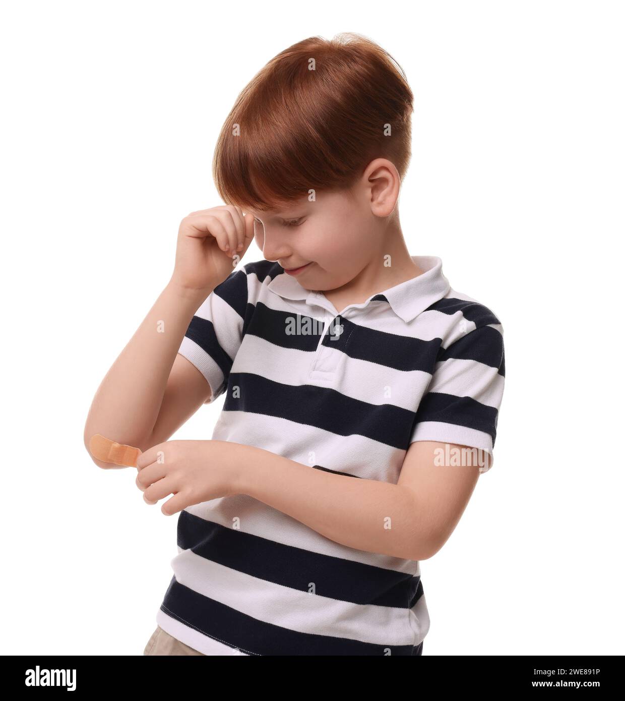 Little boy putting sticking plaster onto elbow on white background ...