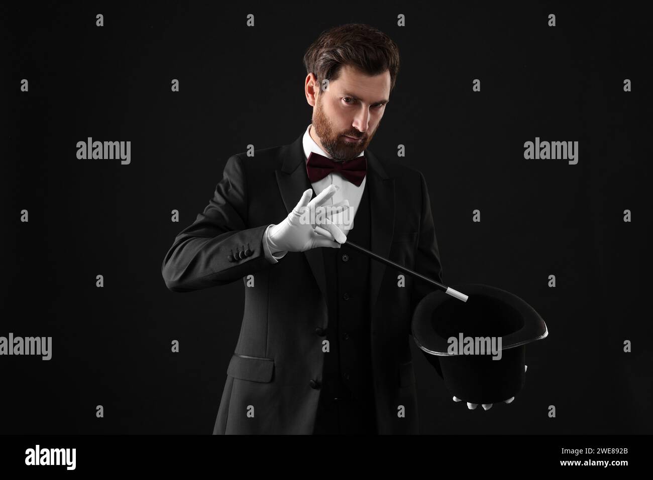 Magician showing magic trick with top hat on black background Stock ...