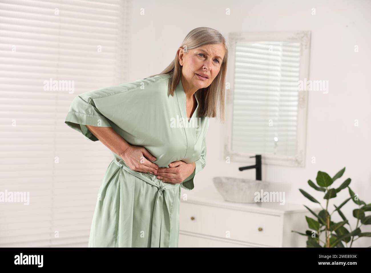 Menopause. Woman suffering from digestive problems in bathroom, space ...