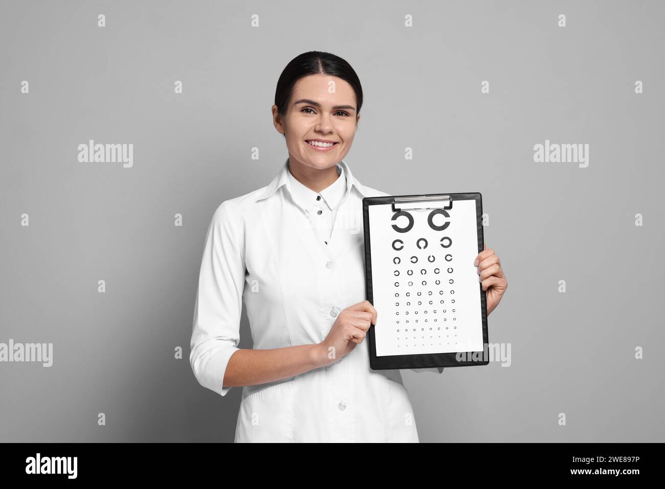 Ophthalmologist with vision test chart on gray background Stock Photo ...