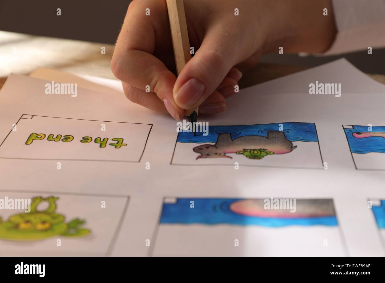 Woman drawing cartoon sketch in storyboard at workplace, closeup. Pre ...