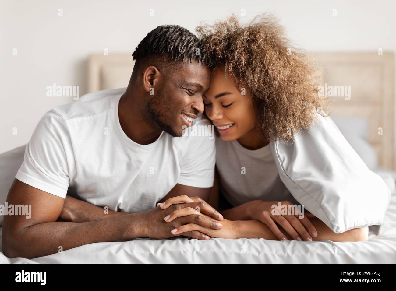 African Young Couple Holding Hands And Touching Foreheads In Bed Stock ...