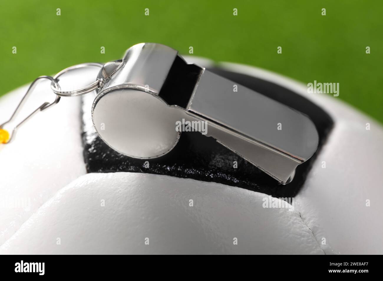 Football referee equipment. Soccer ball and metal whistle on green ...