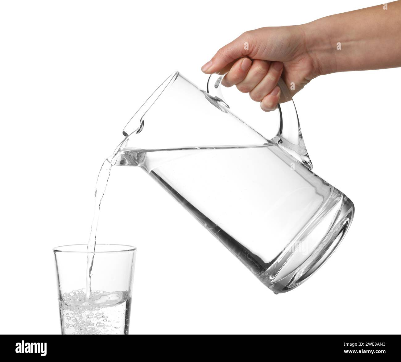Woman pouring water from jug into glass on white background, closeup ...