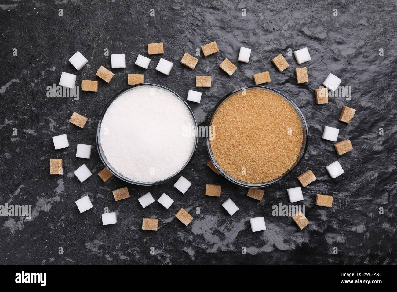 Different types of sugar in bowls on dark gray textured table, flat lay ...