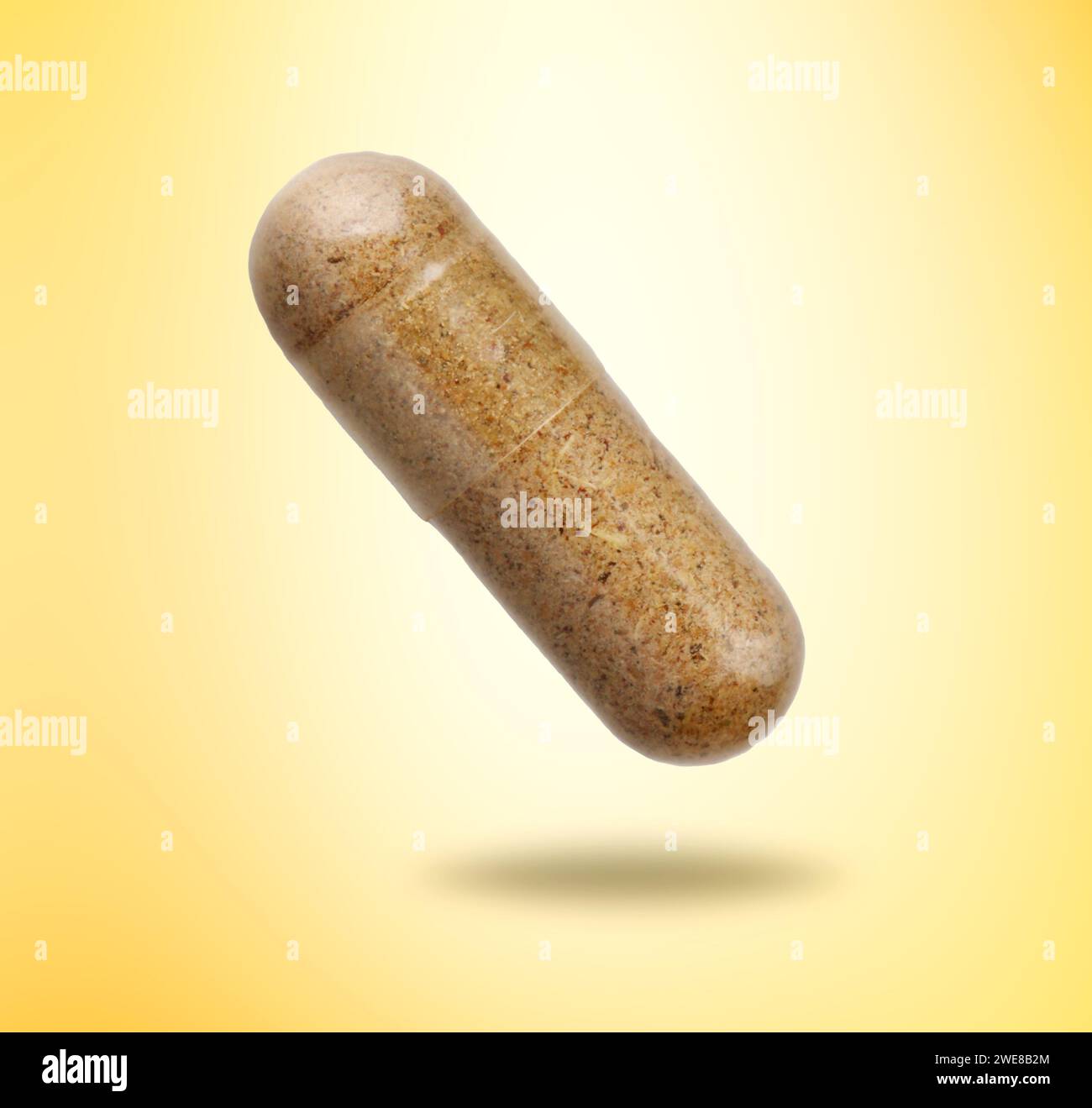 Vitamin capsule in air on yellow gradient background Stock Photo - Alamy
