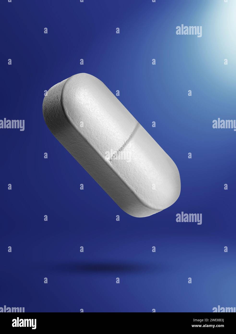Vitamin pill in air on blue gradient background Stock Photo - Alamy
