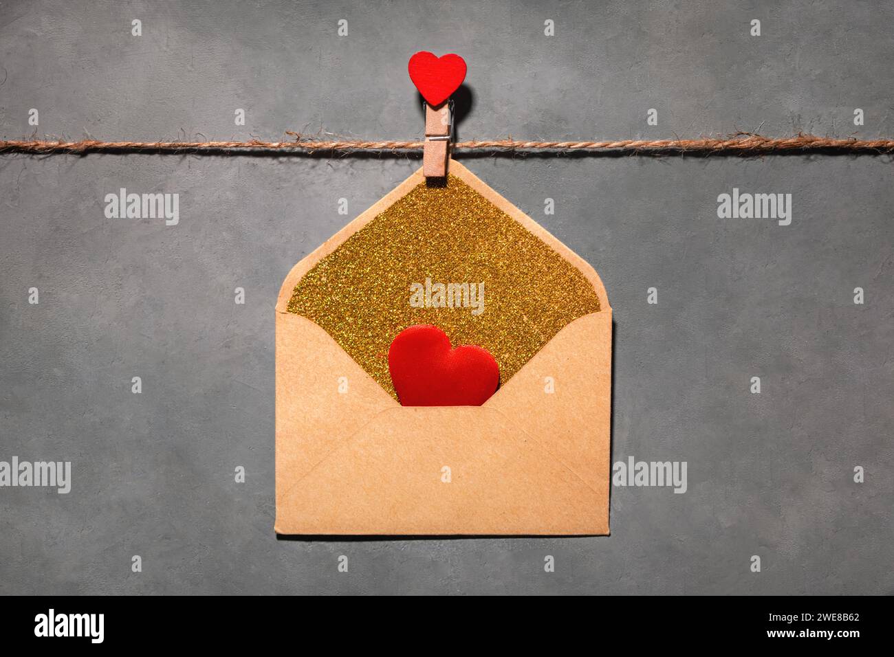 clothespin with red heart on a rope on a gray background. an envelope ...