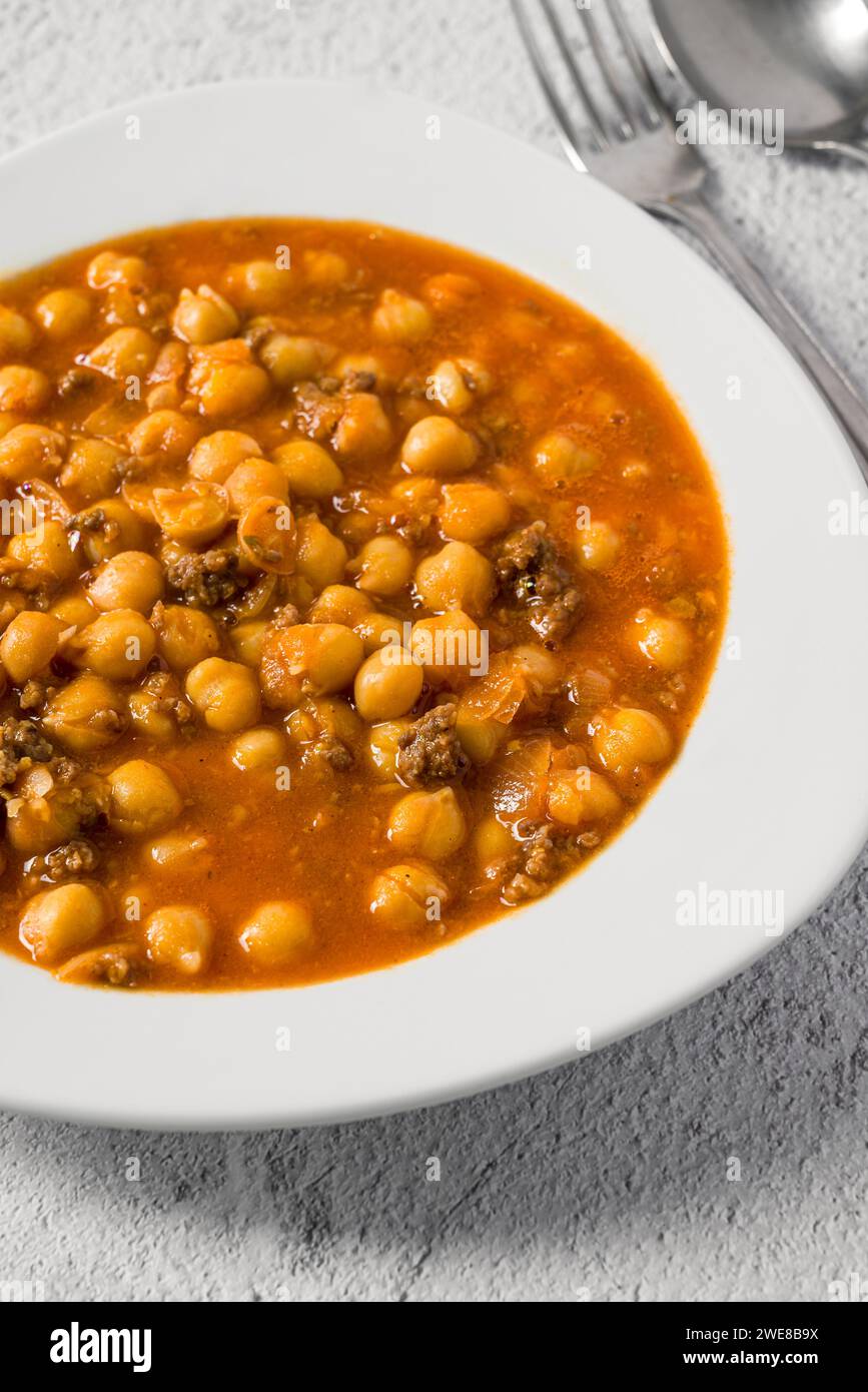 Chickpea stew with minced meat on a white porcelain plate on a stone ...