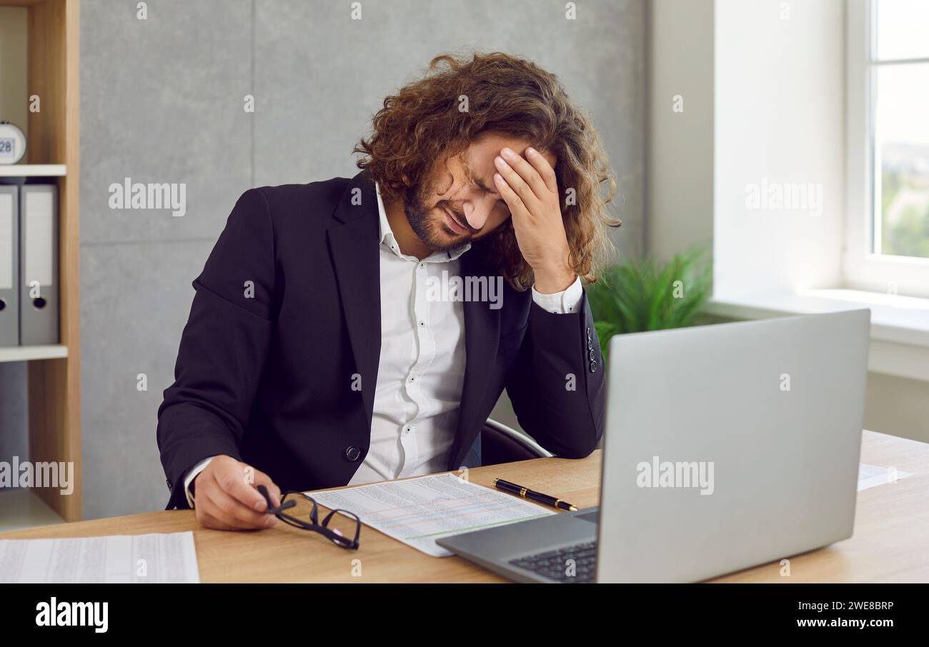 Overworked man having acute headache while working in office due to ...