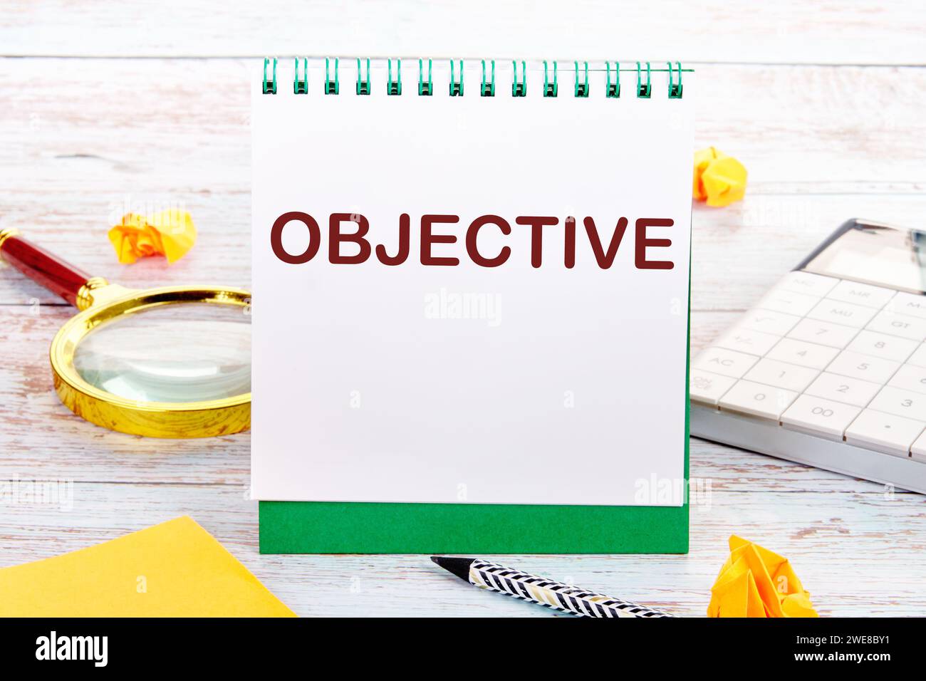 OBJECTIVE text on the white sheet of the notebook is next to a magnifying glass, calculator ...