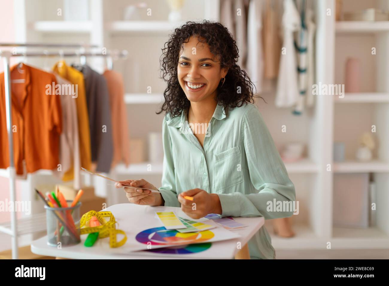 Smiling black lady designer with color swatches in a bright studio ...
