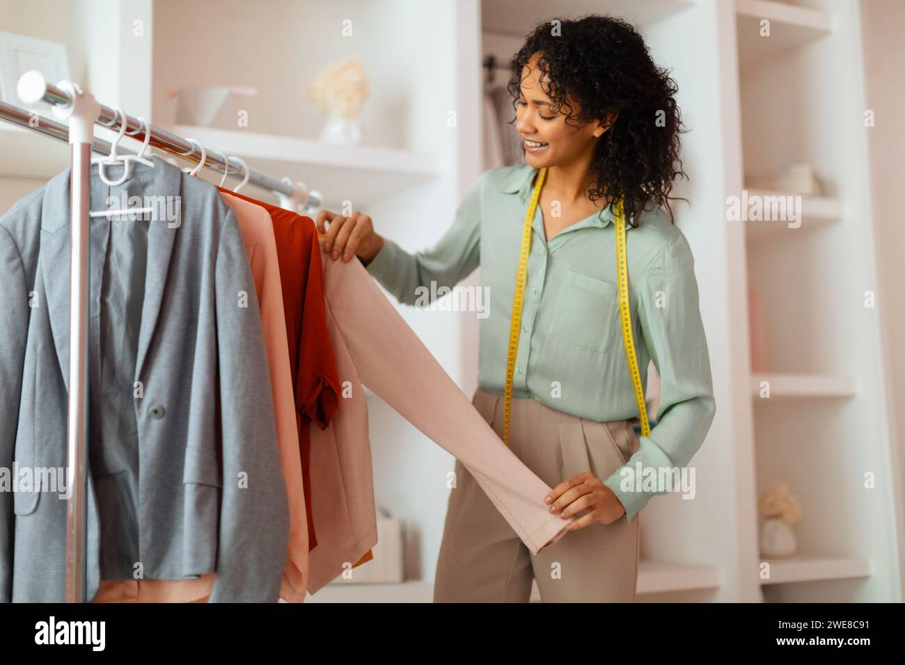 Designer examining fabric quality on clothing rack Stock Photo - Alamy