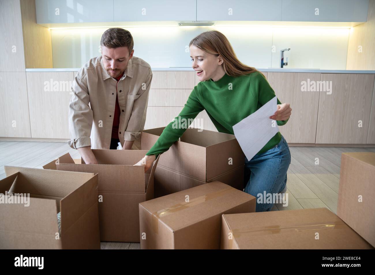 Family couple man woman unpacking boxes with things after moving to new ...