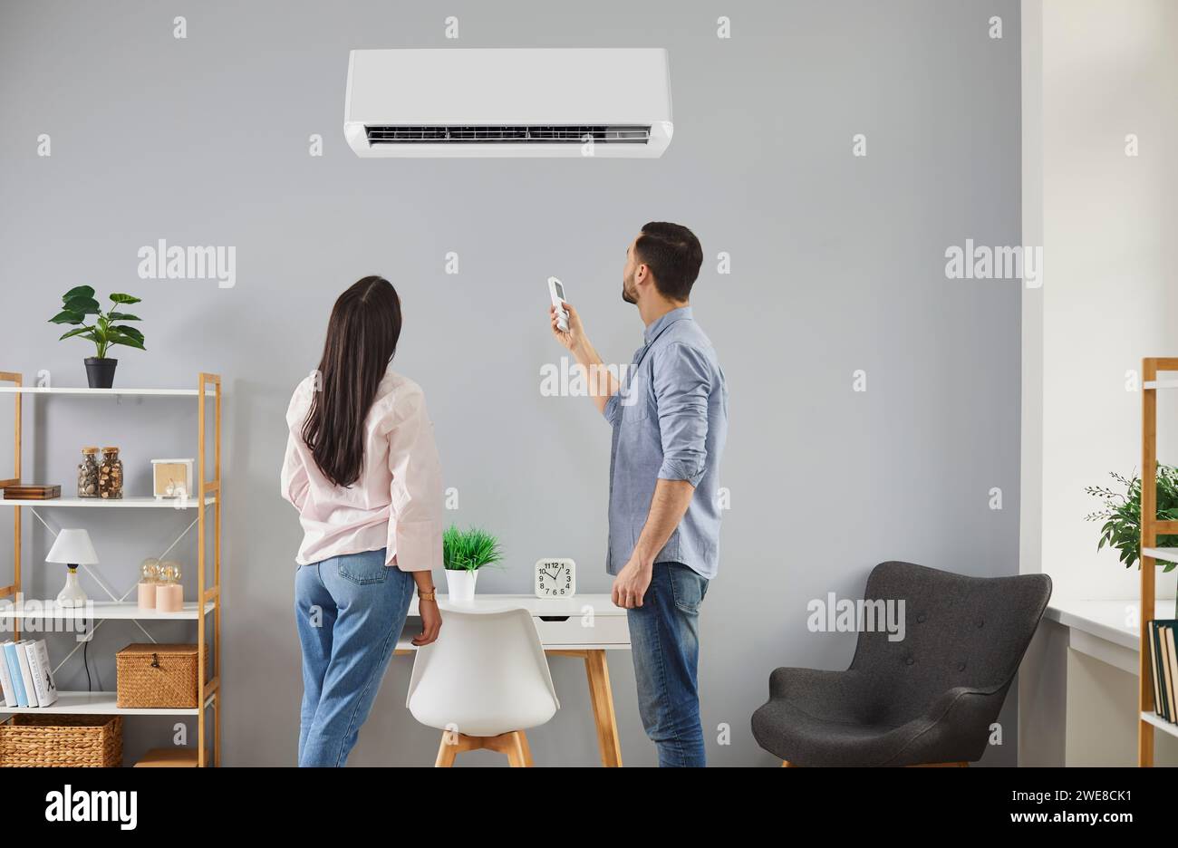 Young family couple regulating temperature at home with modern air conditioning system Stock ...