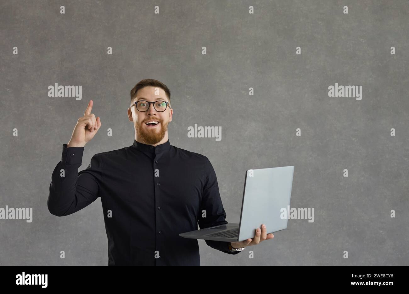 Funny man holding a laptop and pointing his finger up surprised by a ...