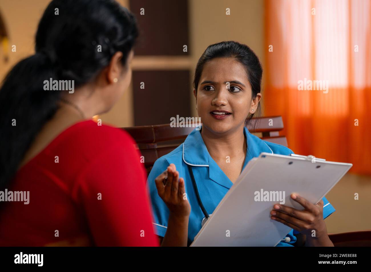 Shoulder shot, Nurse asking questions to sick woman at home during home ...
