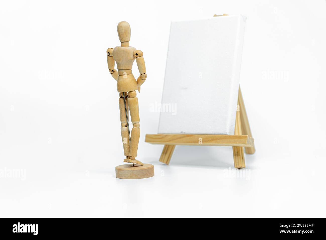 Wooden doll with empty easel on white background; business or creative ...