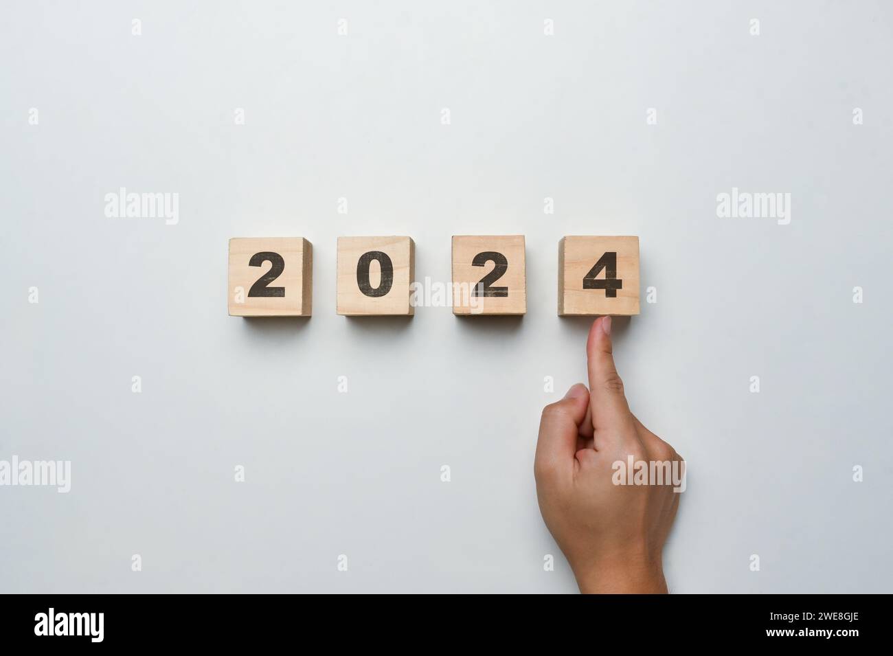Hand pointing Wooden cube blocks with 2024 text on white background ...