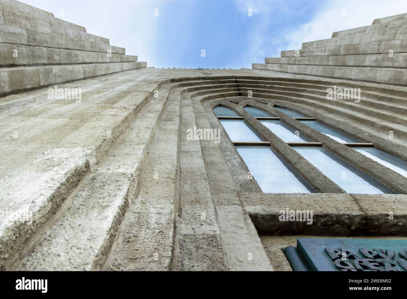 From below exterior of aged stepped concrete facade with arched glass ...