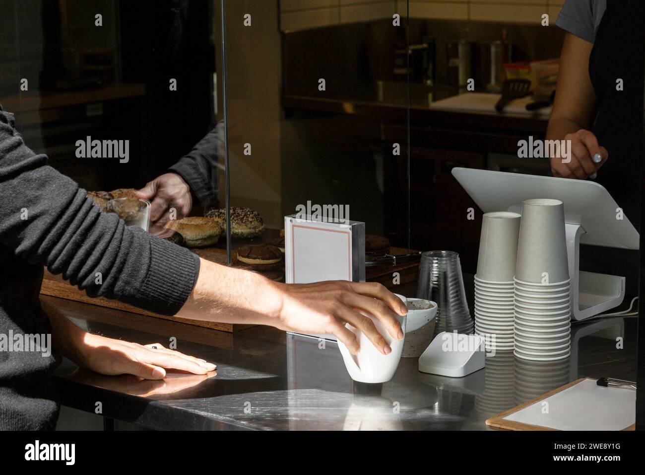 Customer standing at the cafe counter, carefully selecting and placing ...
