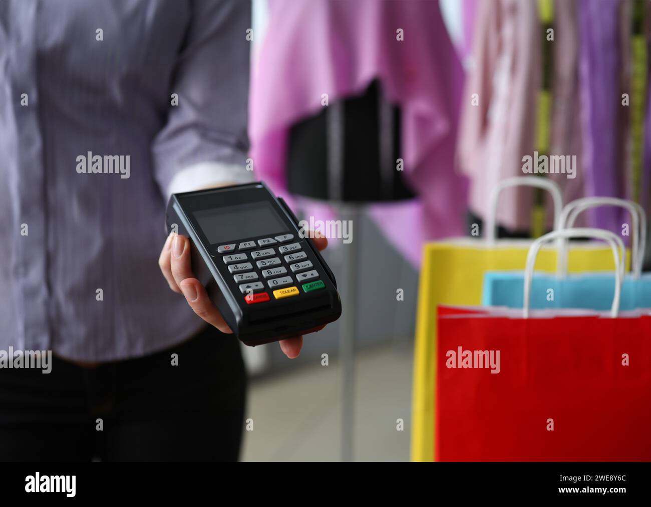 Woman at store holds out customer pos terminal Stock Photo - Alamy