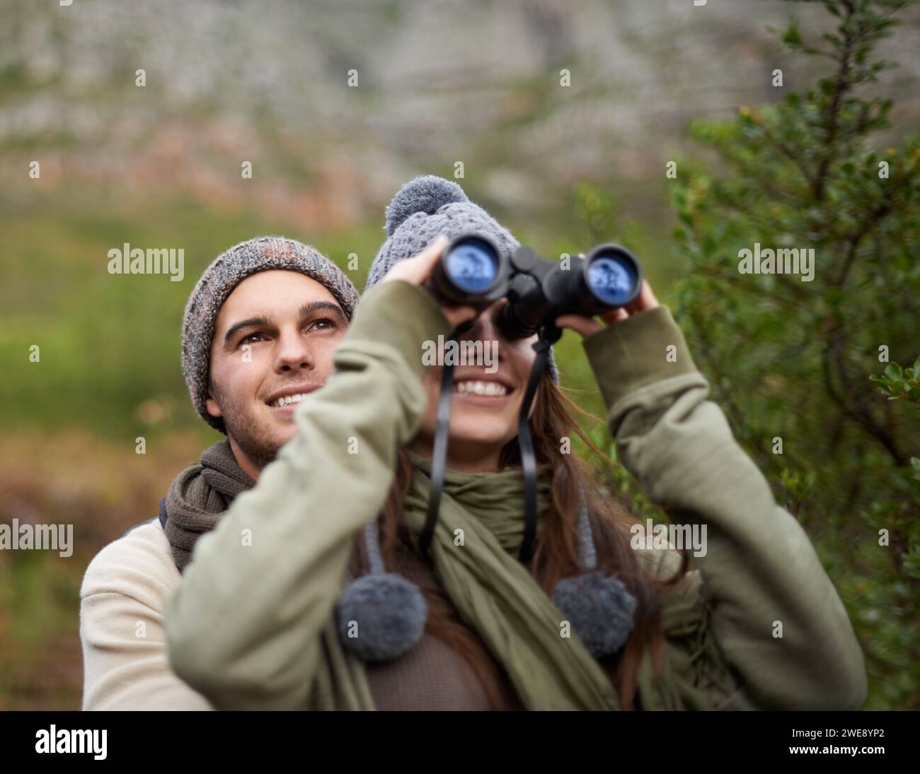 Couple, love and binocular in nature for travel, adventure or hiking ...