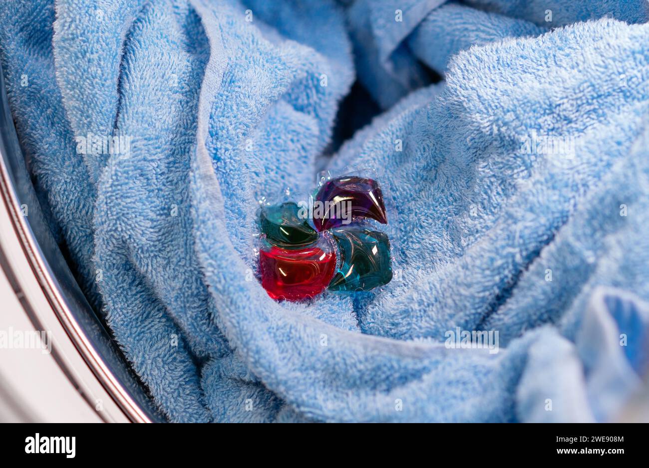 Laundry detergent capsule in washing machine drum on a blue towel ...