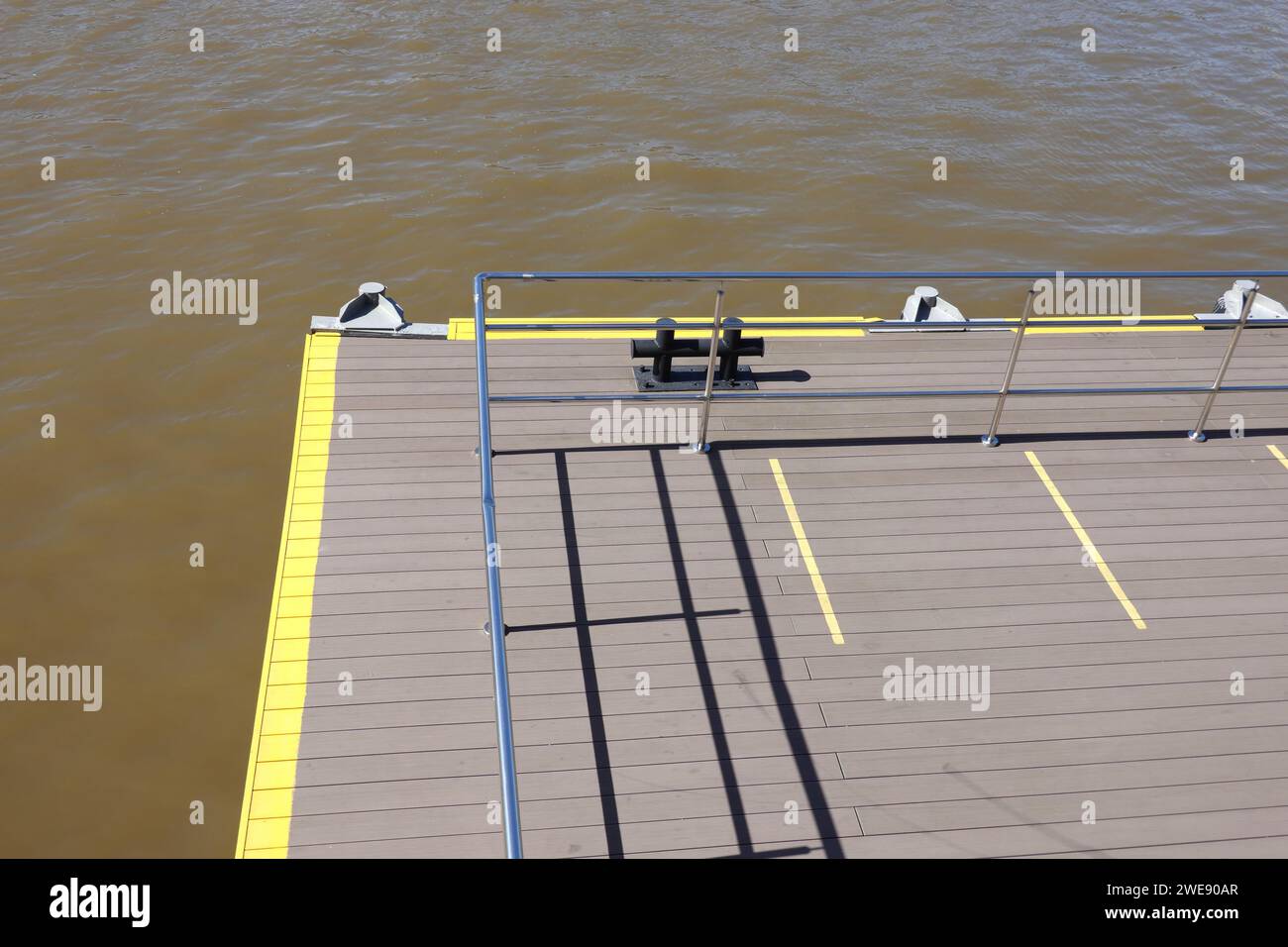 Edge of the jetty with yellow marking line and metal handrail fencing ...