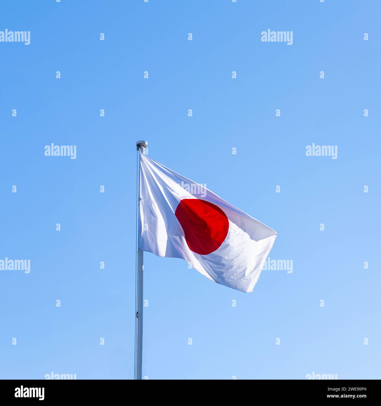 The Japanese flag with a blue sky on the background Stock Photo - Alamy