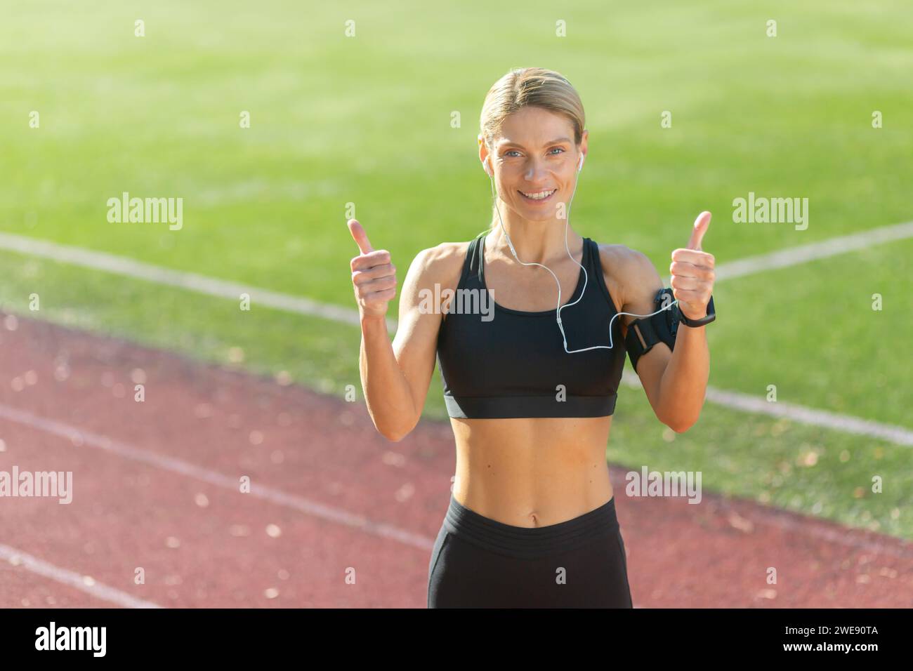 Athletic woman in sports attire giving a double thumbs up signal on a ...