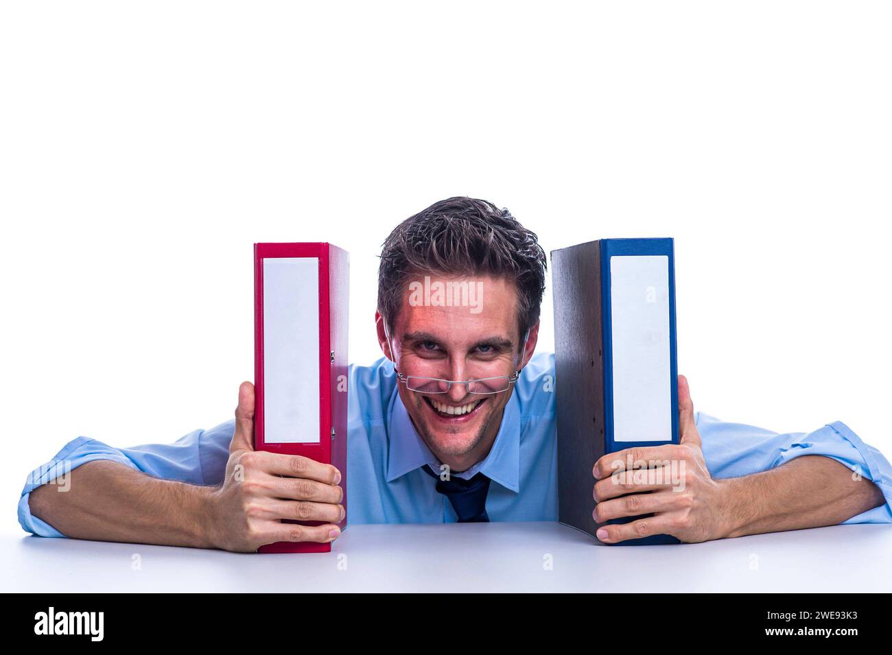 Junger Mann im Büro mit zwei Aktenordner in den Fraben blau und rot. Er ...