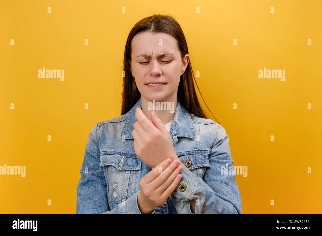Portrait of sad young woman holding painful hand and grimacing in pain ...