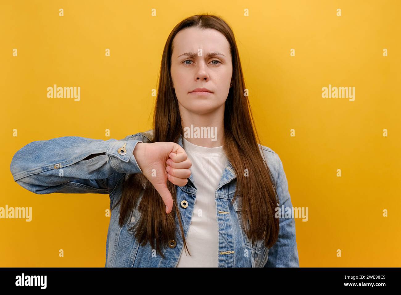 Portrait of upset dissatisfied young woman showing thumb down and ...