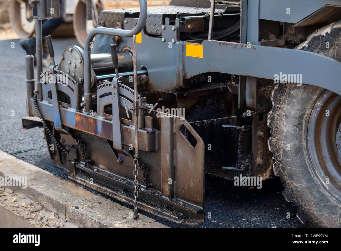 Asphalt paver filled with hot tarmac laying new road surface on new ...