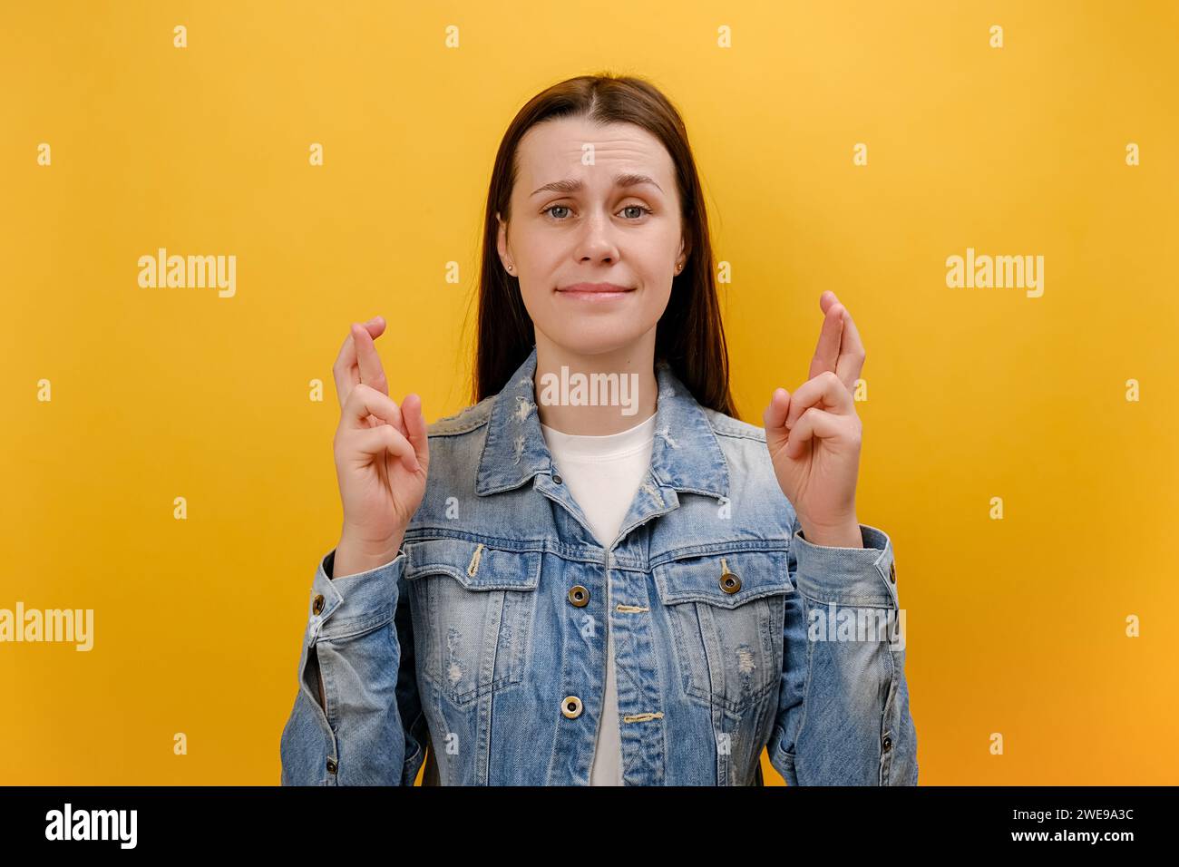 Portrait of young woman standing with crossed fingers for good luck ...