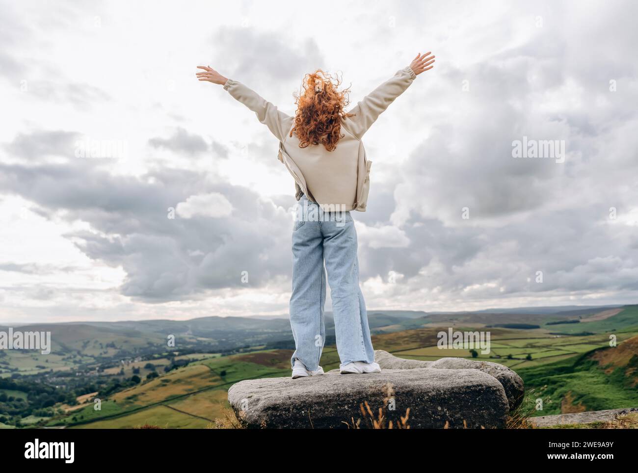 excited woman in jacket reaching the destination, rising her arms and ...