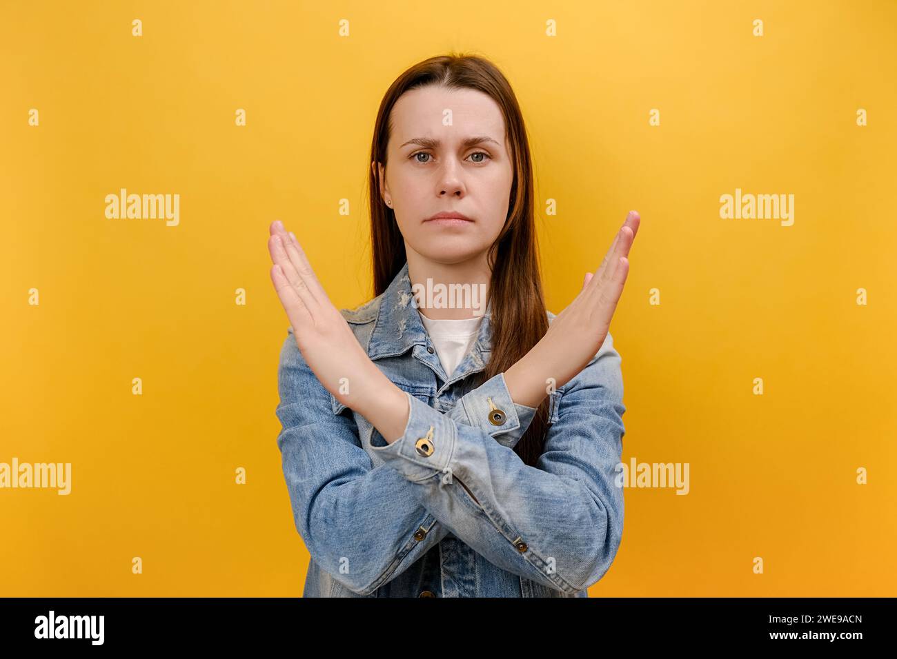 Portrait of serious young woman crossing hands, showing x sign, stop ...