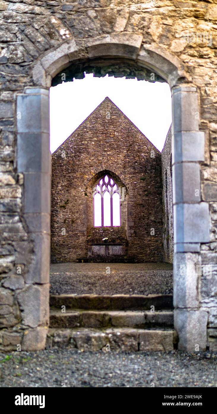 Stone archway leading to a Gothic window in ancient church ruins, with ...