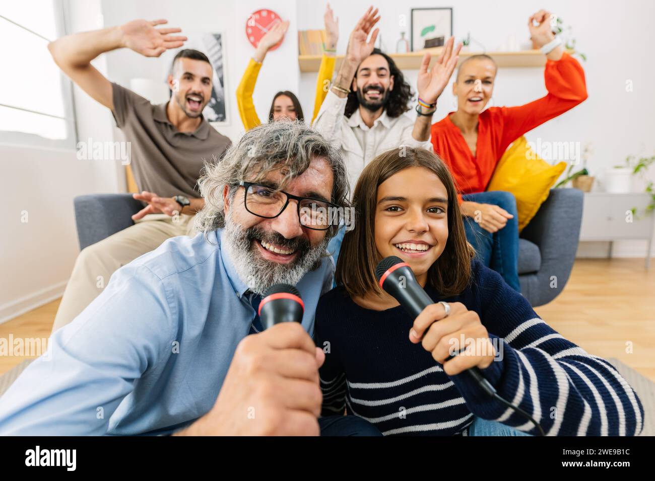Multi-generational family having fun playing karaoke at home Stock ...