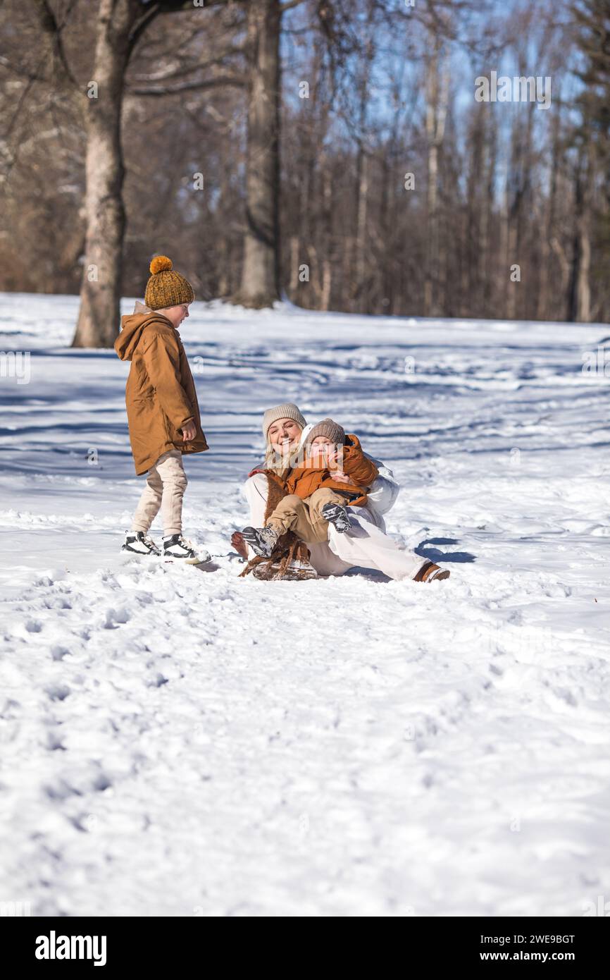 Winter weekend. Mother and two sons in warm winterwear walking while ...