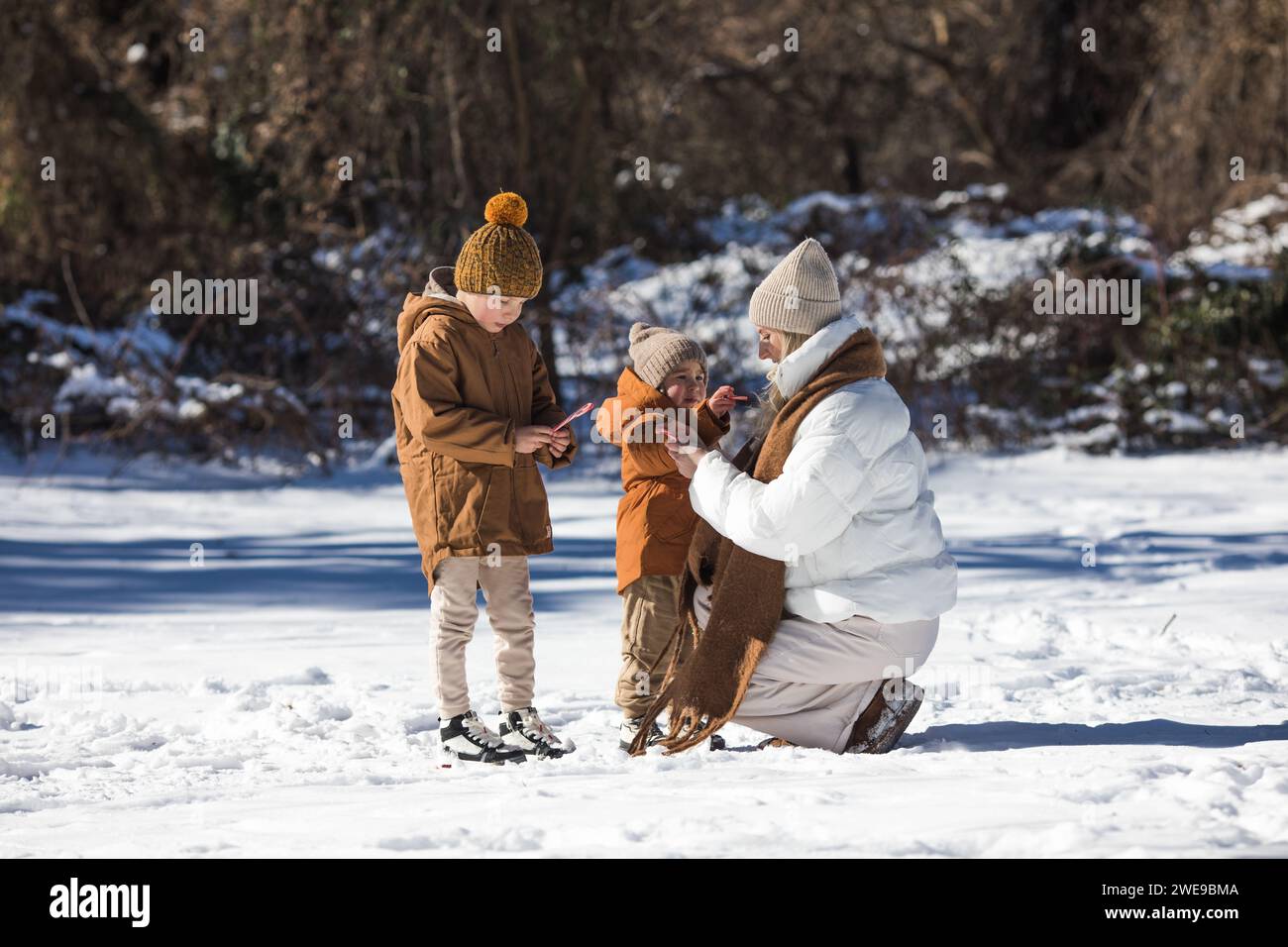 Winter weekend. Mother and two sons in warm winterwear walking while ...