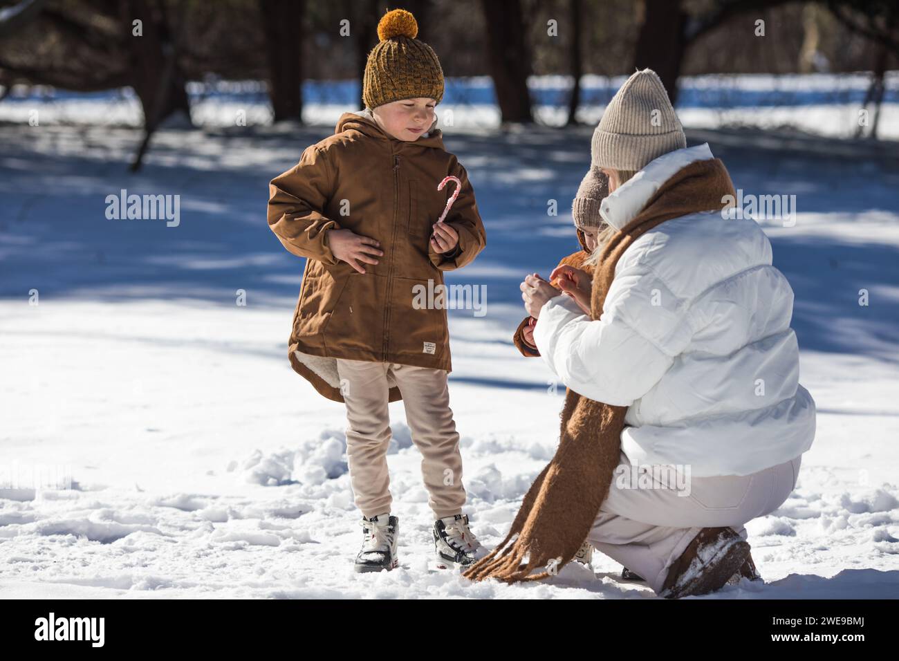 Winter weekend. Mother and two sons in warm winterwear walking while ...