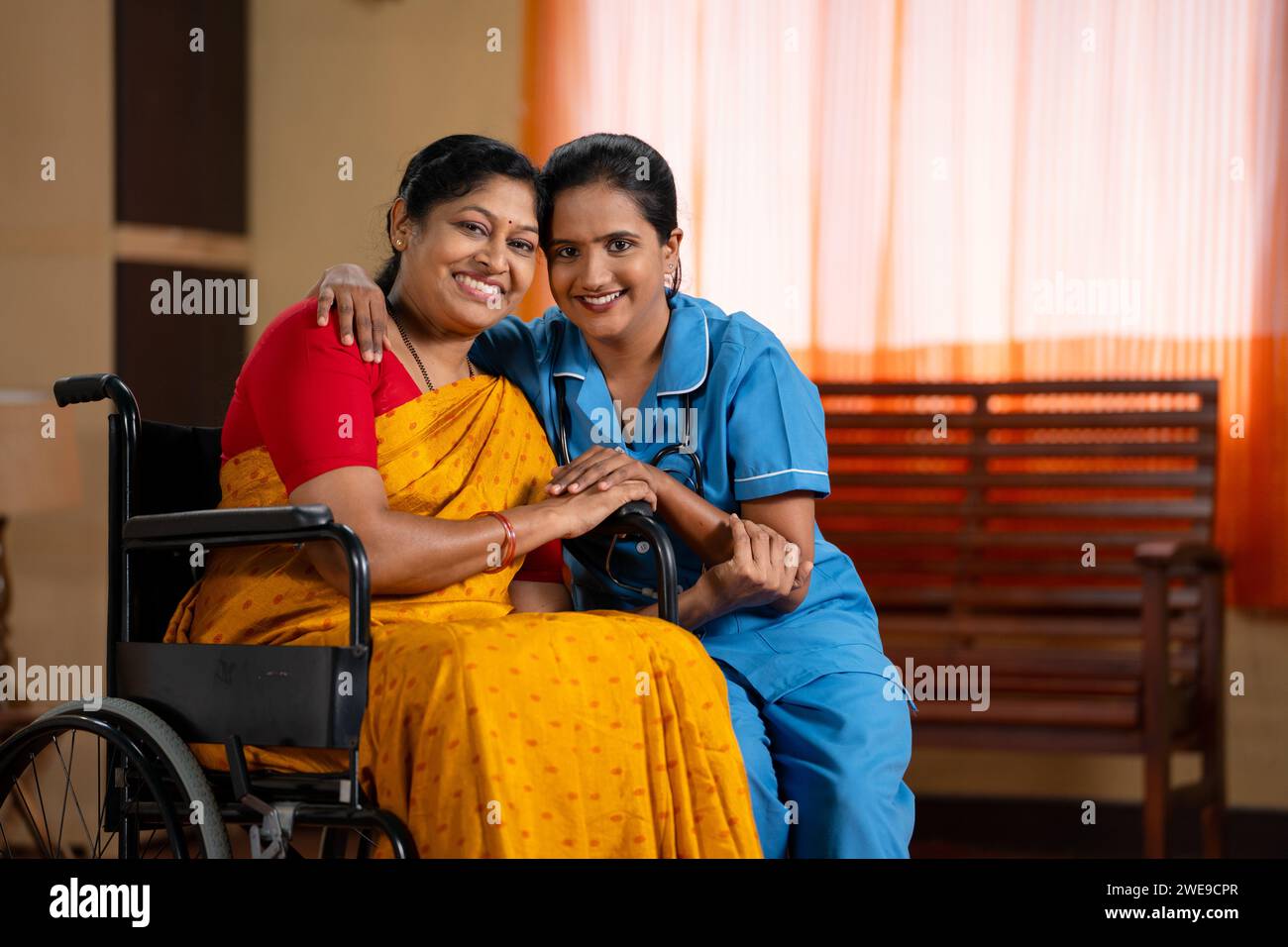 Happy recovered woman on wheelchair with caretaker looking camera at ...