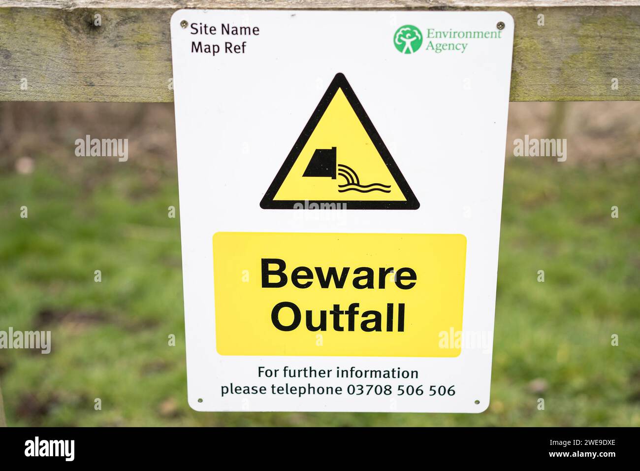 Yellow, black and white beware outfall sign Stock Photo - Alamy