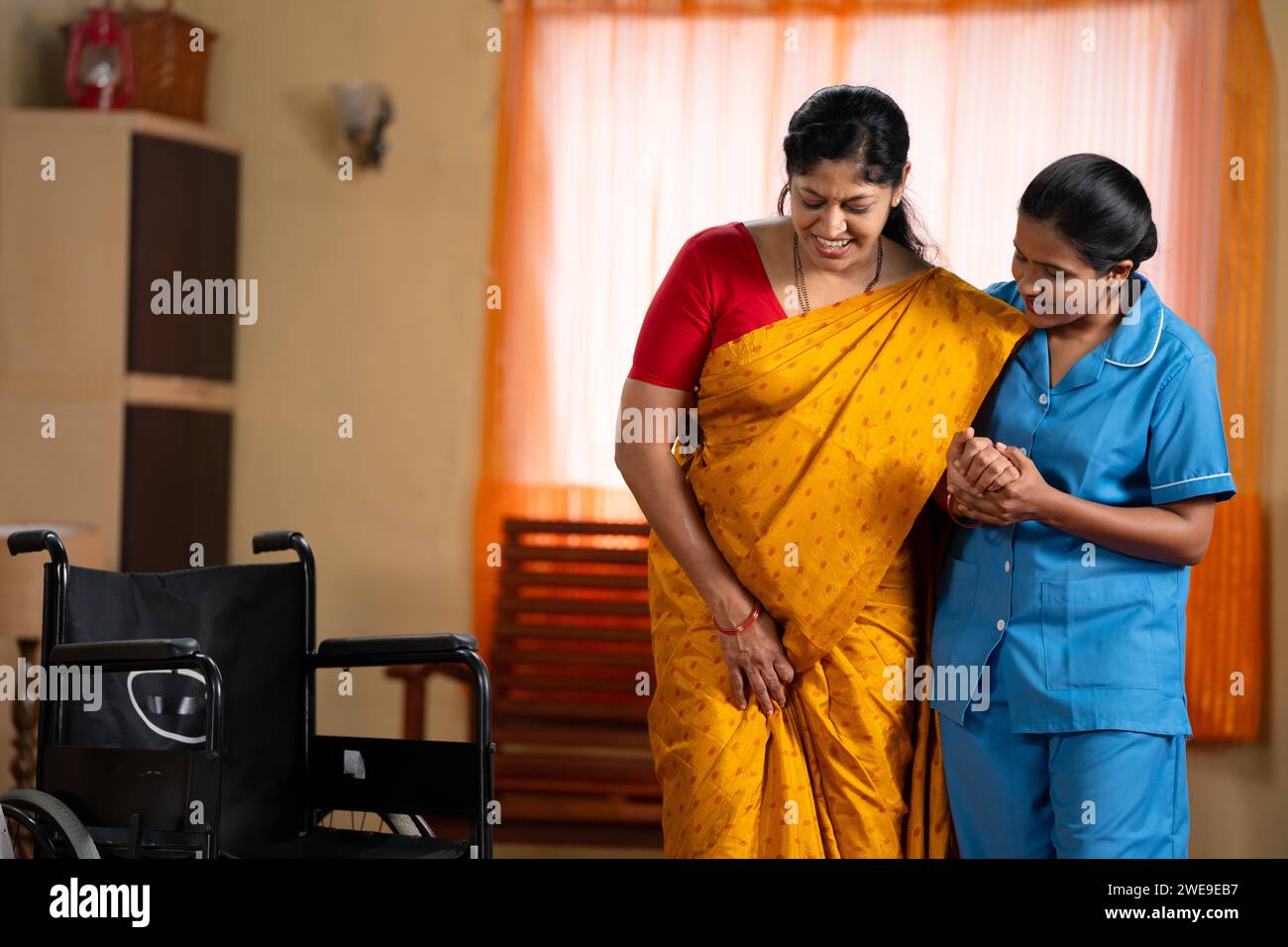 Nurse at home helping injured woman walk at home during therapy session - concept of ...