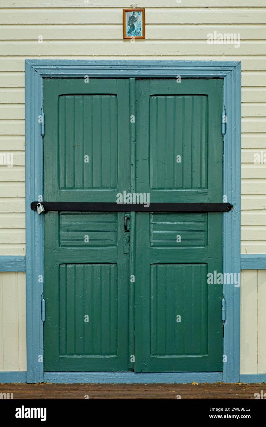 Barred old green wooden doors on a yellow painted wooden building Stock ...