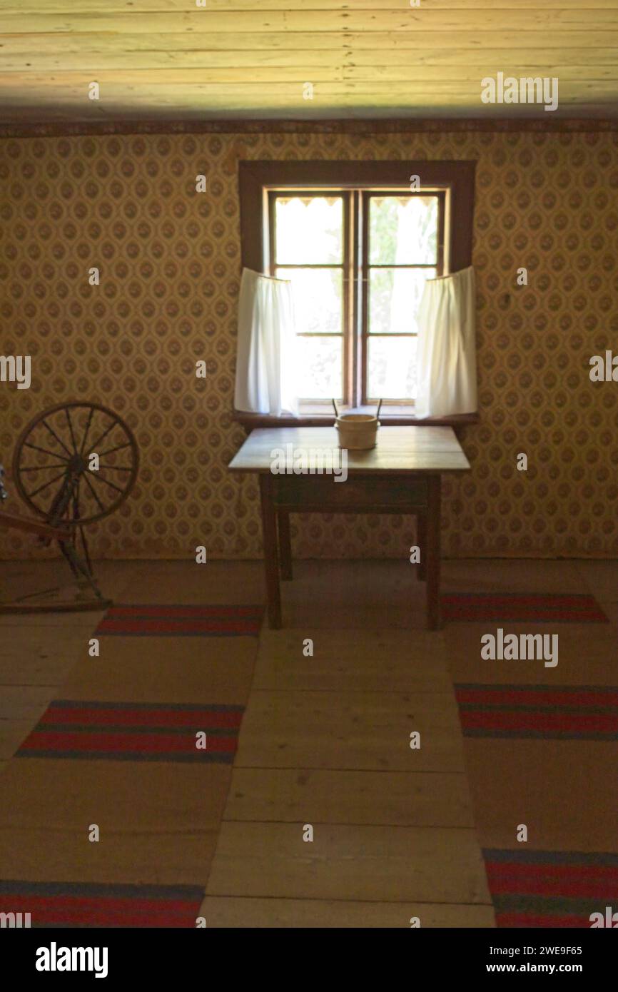 Vintage room with window, desk, spinning wheel and rug in old rural ...