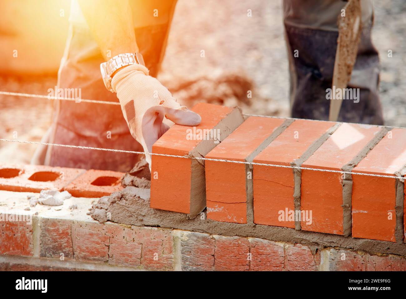 Industrial bricklayer laying bricks on cement mix on construction site ...