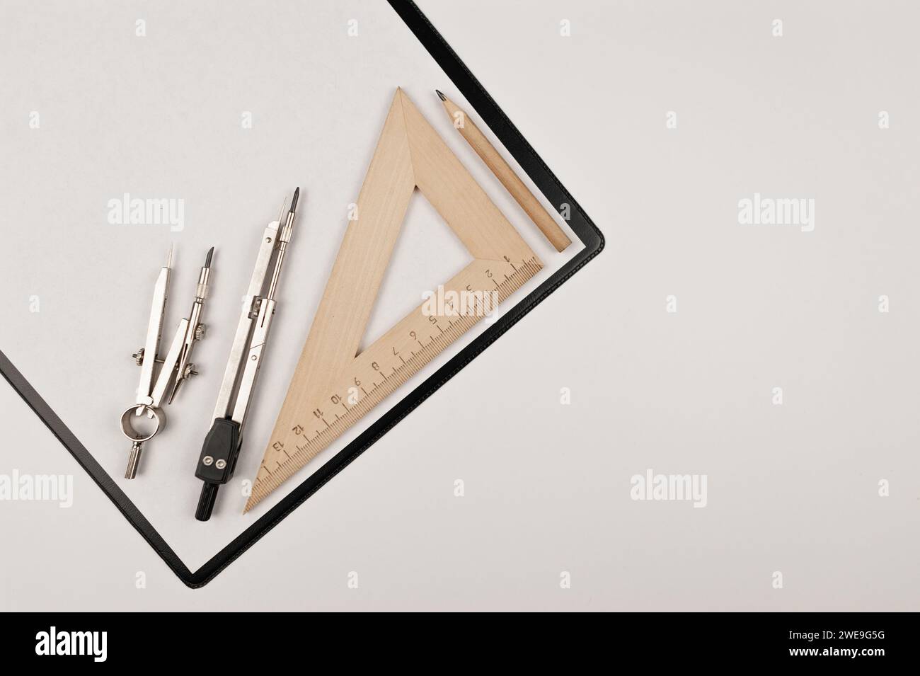 Top view of black clipboard, white blank, triangle ruler, compasses and ...
